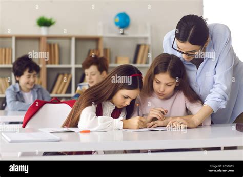 Young Female Teacher Helps Pupil To Make Difficult Task On Lesson At