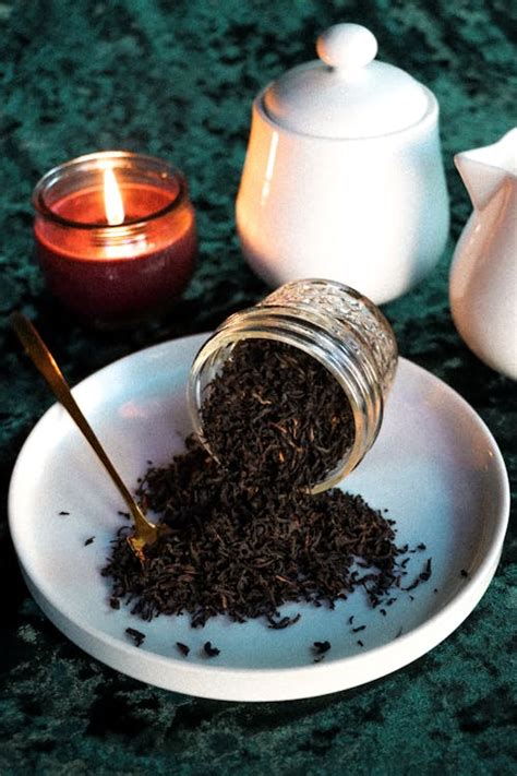 금 숟가락 느슨한 잎차 다도 도자기 따뜻한 조명 무드 조명 불꽃 세라믹 찻 주전자 소프트 포커스 숟가락 쏟은 차 아늑한 아로마 캔들 아로마테라피