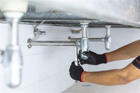 Technician Plumber Using A Wrench To Repair A Water Pipe Under The Sink