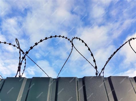 Premium Photo Barbed Wire Over A Prison Fence Against A Blue Sky With