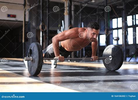 Fit And Muscular Man Doing Horizontal Push Ups With Barbell In Gym