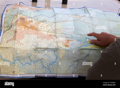 a person points at a detailed topographic map aiding in navigation and