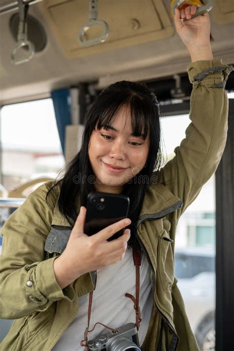 A Positive Asian Female Solo Traveler Using Her Smartphone While
