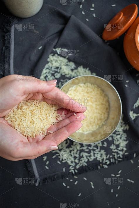 撒了一粒米，一把米，米在一个金属碗上，背景是黑色的。素材 花瓣网
