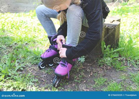 Sunny Spring Day A Blonde Girl Sits On The Park And Puts On Roller
