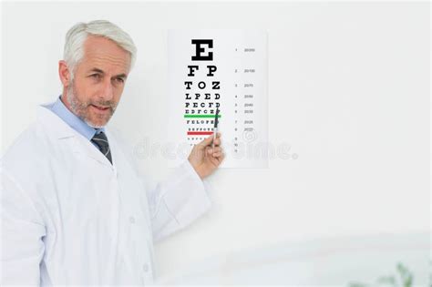 Senior Male Optometrist Holding Pointer And Pointing At Snellen Eye