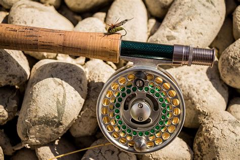 A Close Up Of A Trout Fly Rod Reel And Line On Rocks With A Cicada