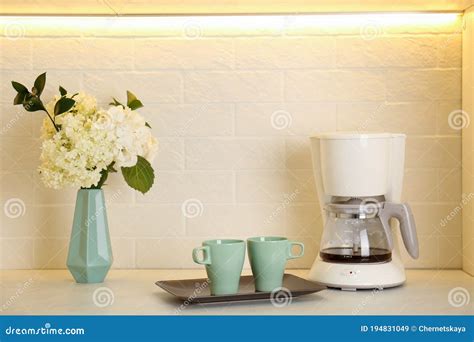 Bouquet With White Hydrangea Flowers Coffee Maker And Cups On Light