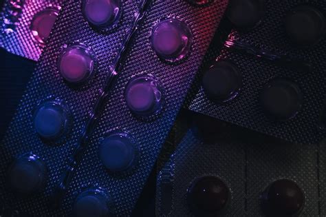 Premium Photo Pills Or Drugs In A Package Under Neon Light On A Dark