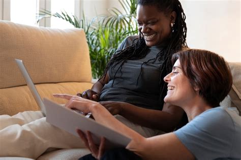 Casal De Lésbicas De Vista Lateral Com Laptop Em Casa Foto Grátis