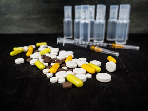 Pills In A Jar Syringe For Injection Vaccine On A Black Background