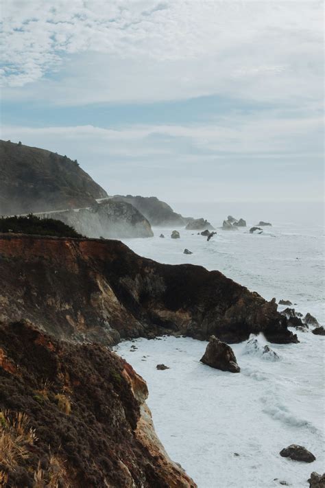 A Rocky Beach With A Body Of Water And A Rocky Cliff Photo Free Beach