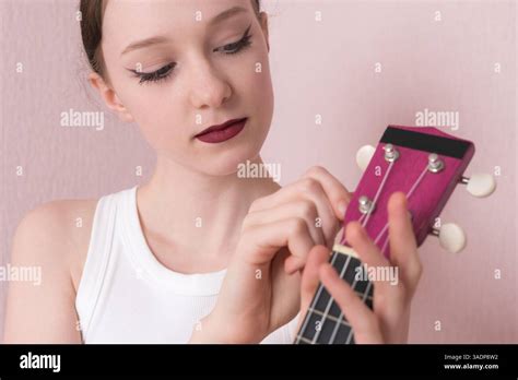 Woman Musician Holding Ukulele And Tuning Strings She Is Tightening
