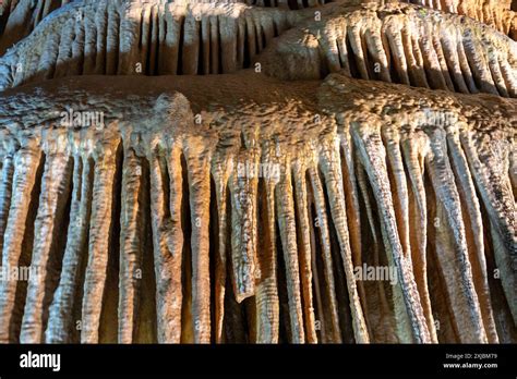 A Detailed View Of Stalactites In A Cave Characterized By Elongated