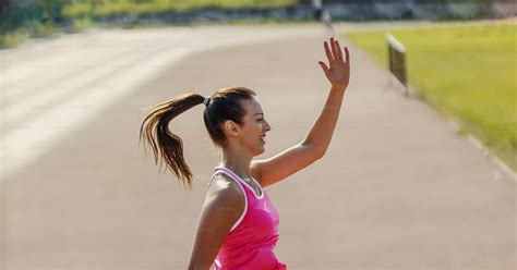 운동 트랙에서 높은 점프 스포티 한 검은 색과 분홍색 옷과 흰색 운동화를 입은 잘 생긴 여성이 강한 움직임으로 뛰어 오른다 화창한 여름날 밖에서 경쟁할 준비 사진