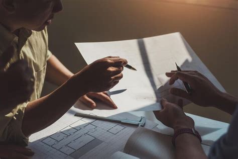 Premium Photo Midsection Of Architects Analyzing Blueprints On Table