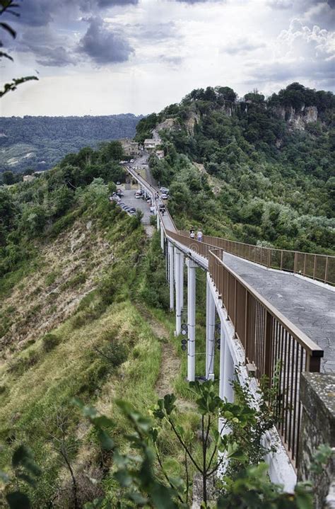 Panoramic View Of Civita Di Bagnoregio Access Bridge And Lush Stock
