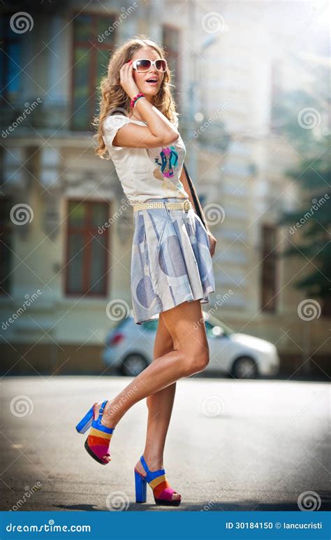 Fashion Girl With Short Skirt Bag And High Heels Walking On Street