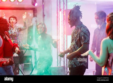 Group Of Friends Dancing At Modern Disco Party In Crowded Nightclub