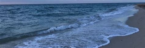 The Ocean Waves Are Coming In To Shore On A Beach At Sunset Or Dawn With An Overcast Sky