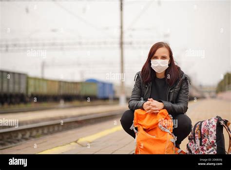 Young Woman In Medical Mask Squats On Platform Waiting For Train