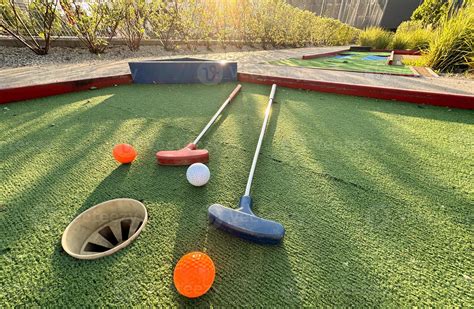 Assorted Miniature Golf Putters And Balls Askew On Synthetic Grass