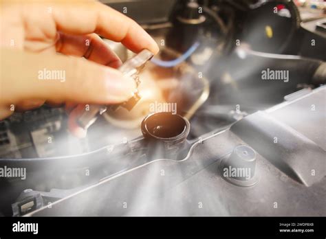 Auto Mechanic Hand Opens The Radiator Cap With Steam Escaping Around The Engine Compartment From