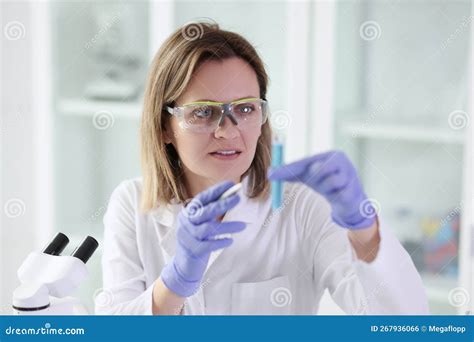 Gloved Female Scientist In Glasses Looking At Sample While Doing