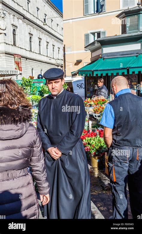 Catholic Priest Wearing A Cassock And A Flat Cap At A Flower Market