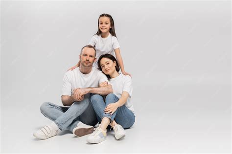Joyous Preteen Girl Hugging Mother And Father In White Tshirts And Blue