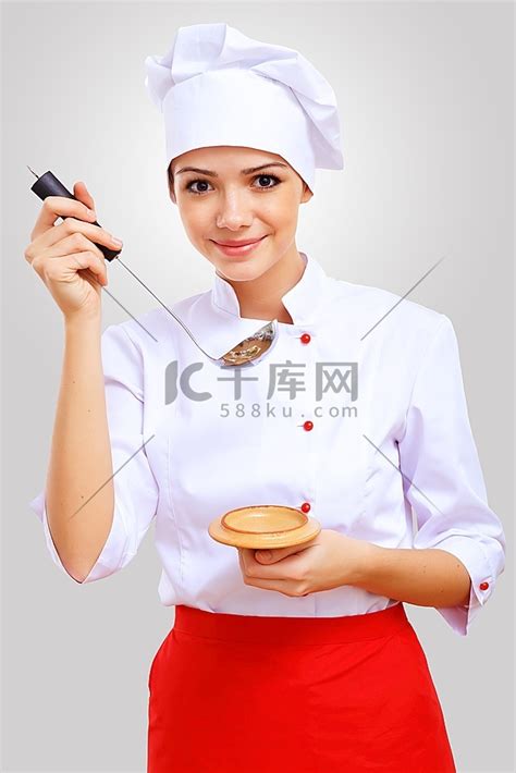 年轻的女厨师在红色围裙反对灰色背景高清摄影大图 千库网