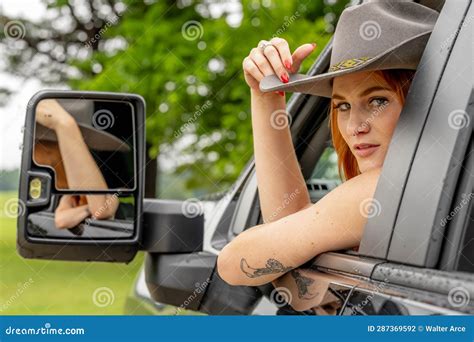 A Lovely Redhead Model Sits In Her Truck While Wearing A Cowboy Hat On