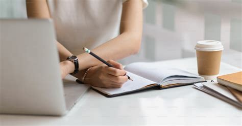 Close Up View Of Female Student Hand Doing Assignment With Laptop And