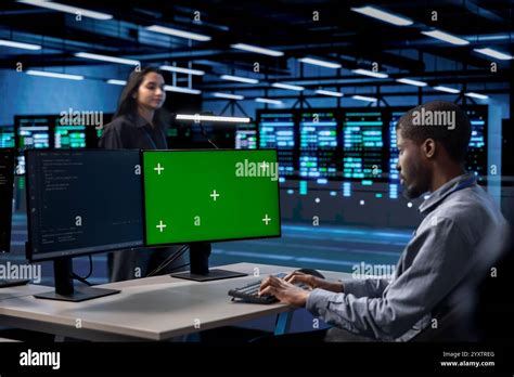 man in data center updating systems on green screen pc to protect