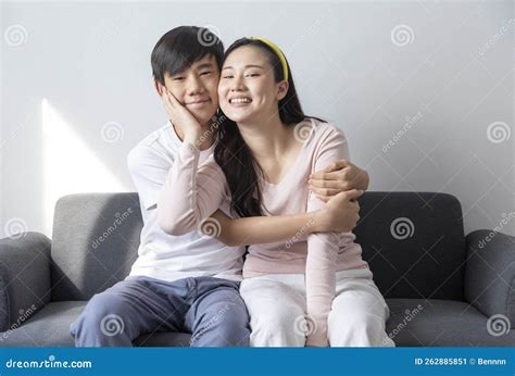Asian Brother And Sister Hugging With Care And Love Sit On Sofa Stock