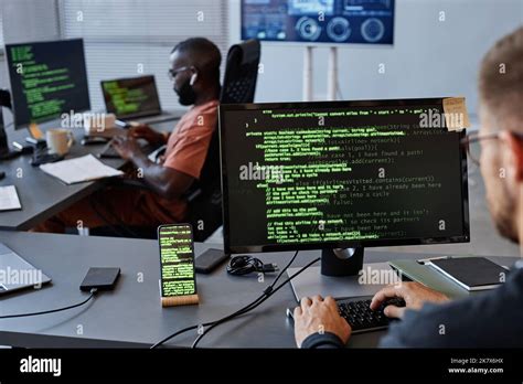 background image of software development office with green code lines on computer screen copy