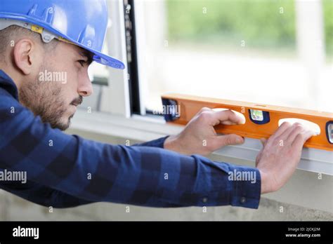 construction worker using bubble level while installing window indoors