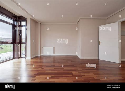 A Living Room With Reddish Wooden Flooring A Window With Dark Red