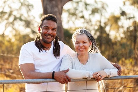 Image Of Happy Aboriginal Australian Couple Leaning On Farm Gate