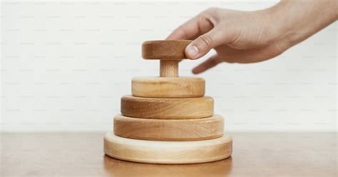 흰 벽 배경에 테이블에 천연 나무 피라미드 반지를 들고 있다 유아를 위한 친환경 플라스틱 무료 현대 장난감 몬테소리 교육과 놀이 어린이를위한 세련 된 간단한 나무