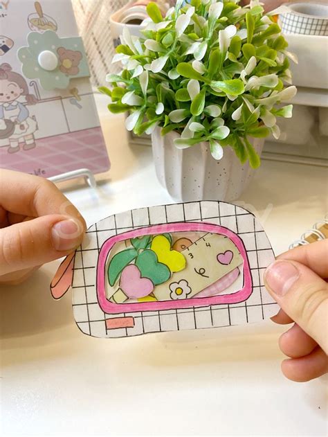 Two Hands Holding Up A Small Card With A Cartoon Character On It And A
