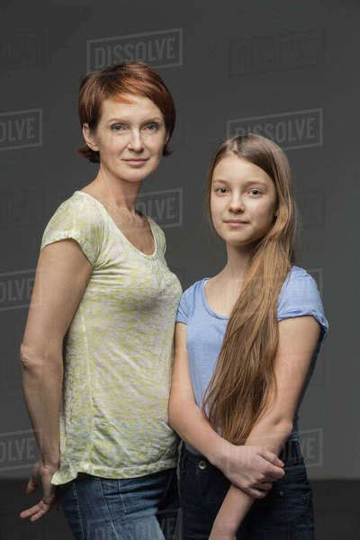 Portrait Of Mother And Daughter Standing Against Gray Background