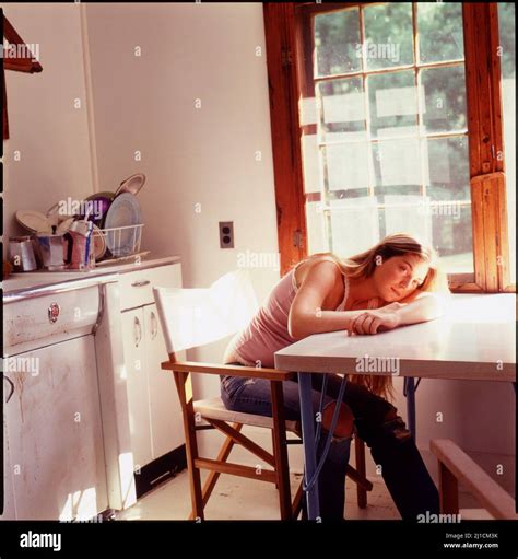 Casually Dressed Young Woman Seated At Her Kitchen Table Her Head