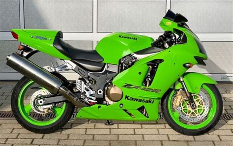 Kawasaki Motorcycle Parked In Front Of Building Motos Antigas Vans