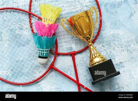 Gold Cup With Badminton Rackets And Shuttlecocks On Grunge Background