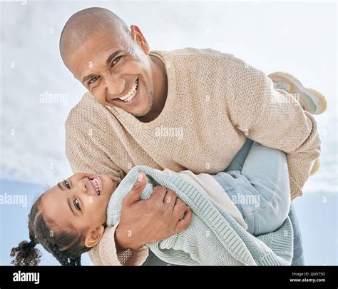 Portrait Of Cheerful Latino Father From Below Carrying His Cute Little Daughter While Bonding