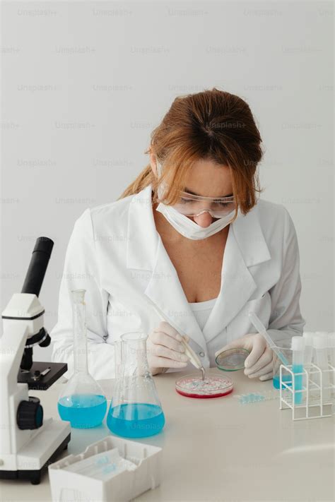 하얀 실험실 코트를 입은 여자가 뭔가를하고 있습니다 사진 Unsplash의 과학자 이미지