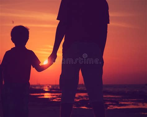 Silhouette Di Un Padre E Un Figlio Che Si Tengono Per Mano Al Tramonto