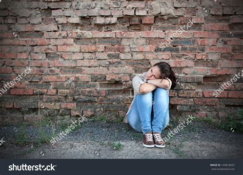 Sad Girl Sitting Against Wall