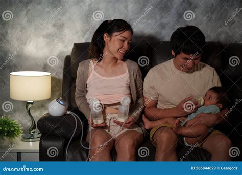 Mother Using Breast Pump Machine To Pumping Milk While Father Feeding